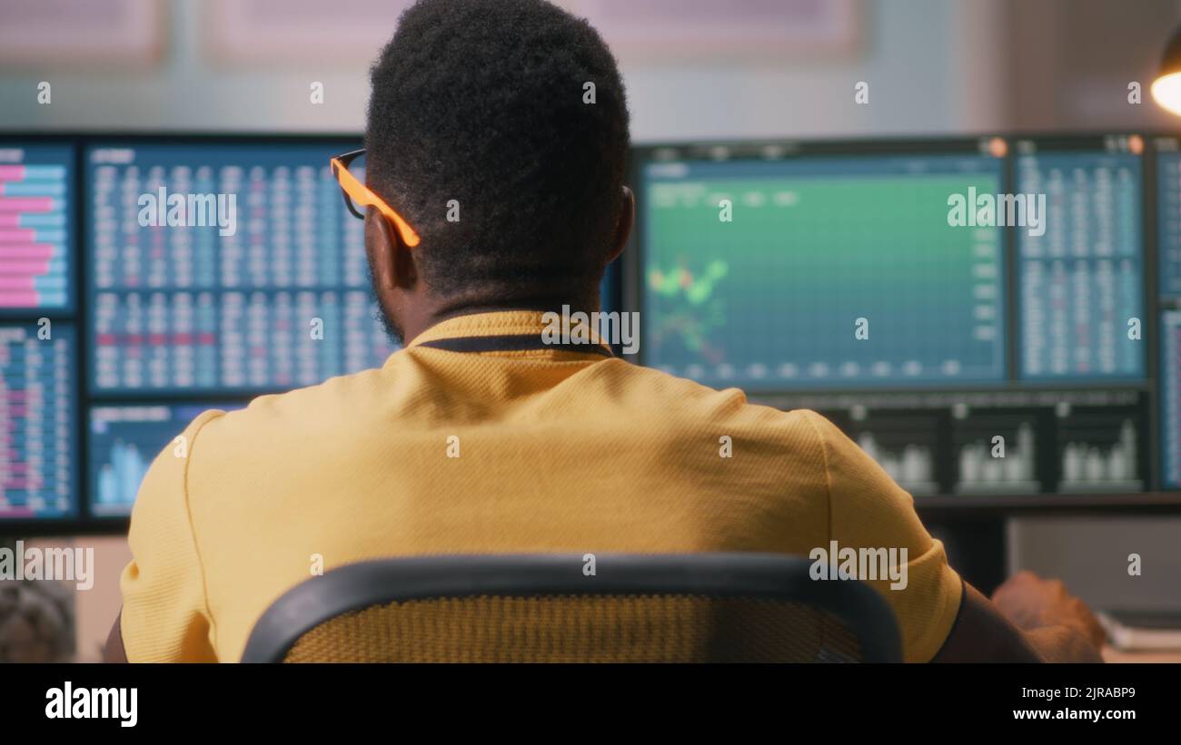 Rack focus of black man in yellow t shirt analyzing financial graphs on ...