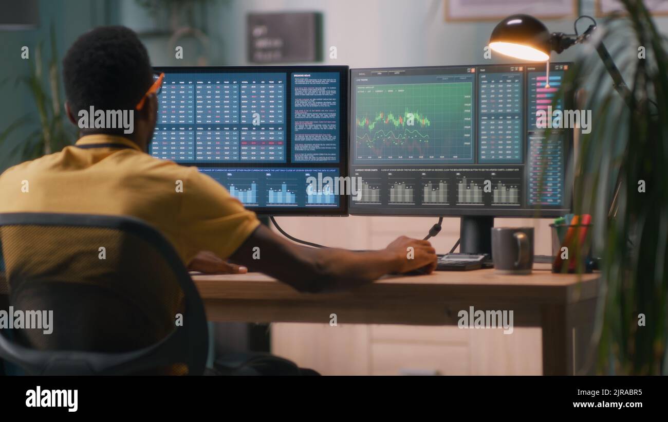 Back view of African American man analyzing data on computers while ...