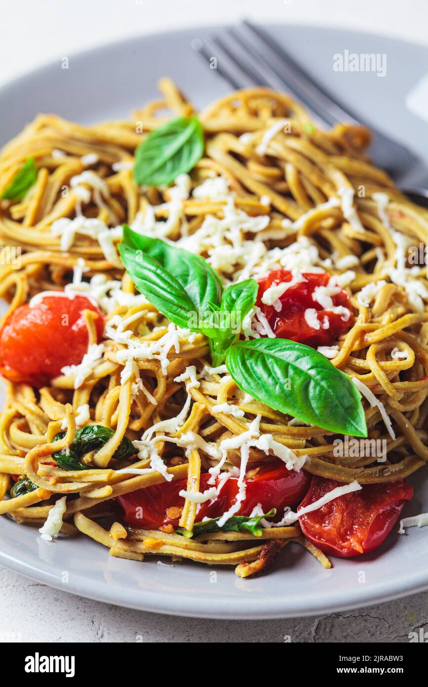 Bean green vegan pasta with tomatoes, basil and nuts cheese in gray ...