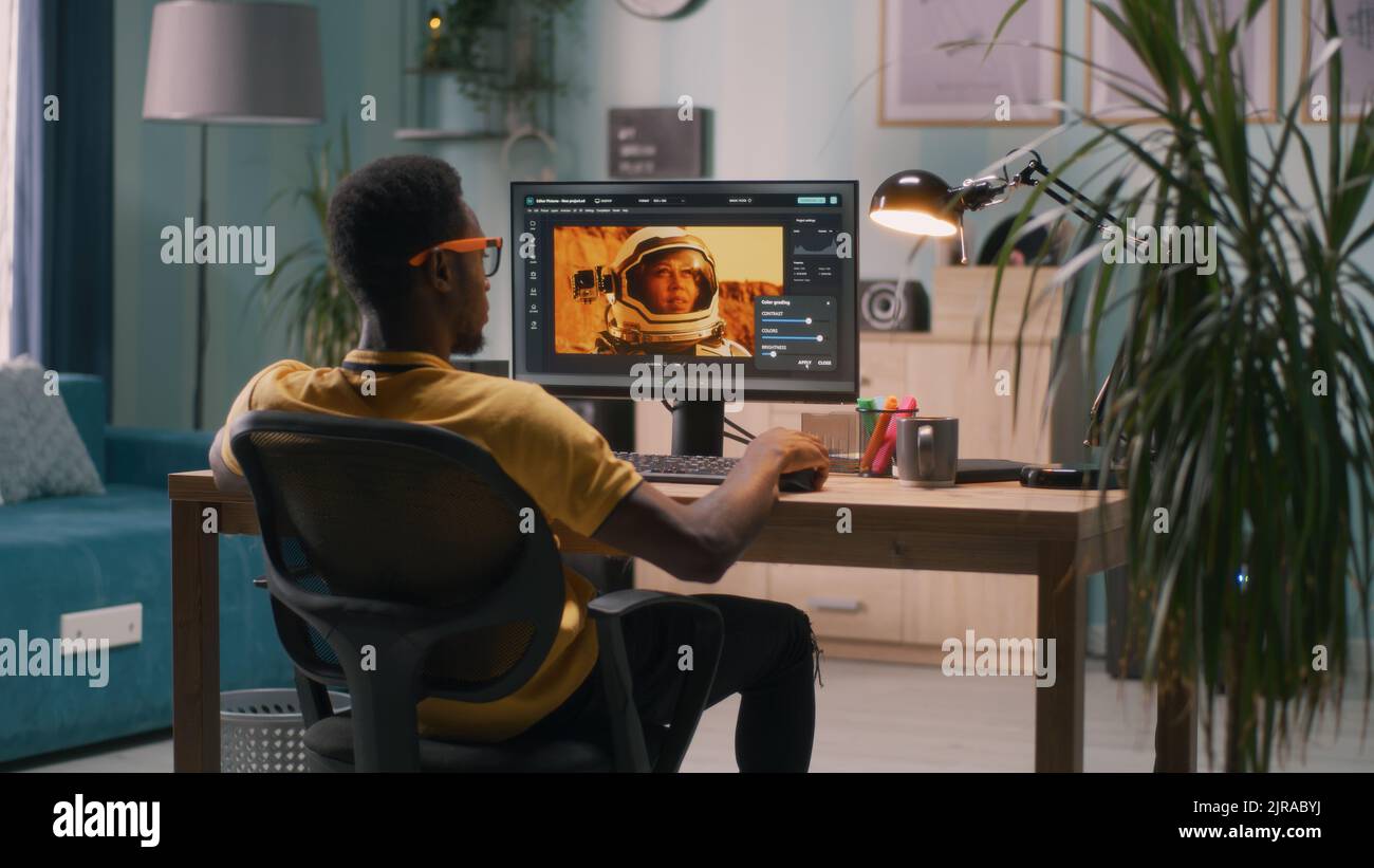 Black man using software on modern computer to edit photo in editing ...