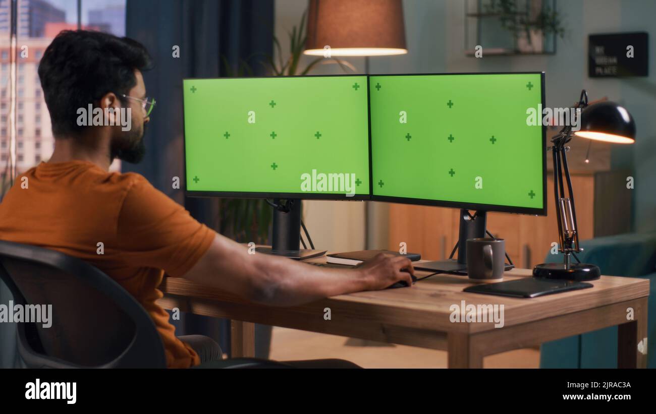 Bearded Indian guy in glasses sitting at table and browsing data on ...