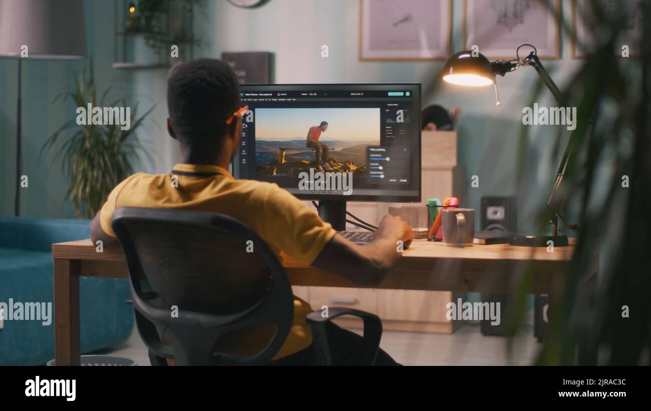 Back view of African American man using software on computer to create ...