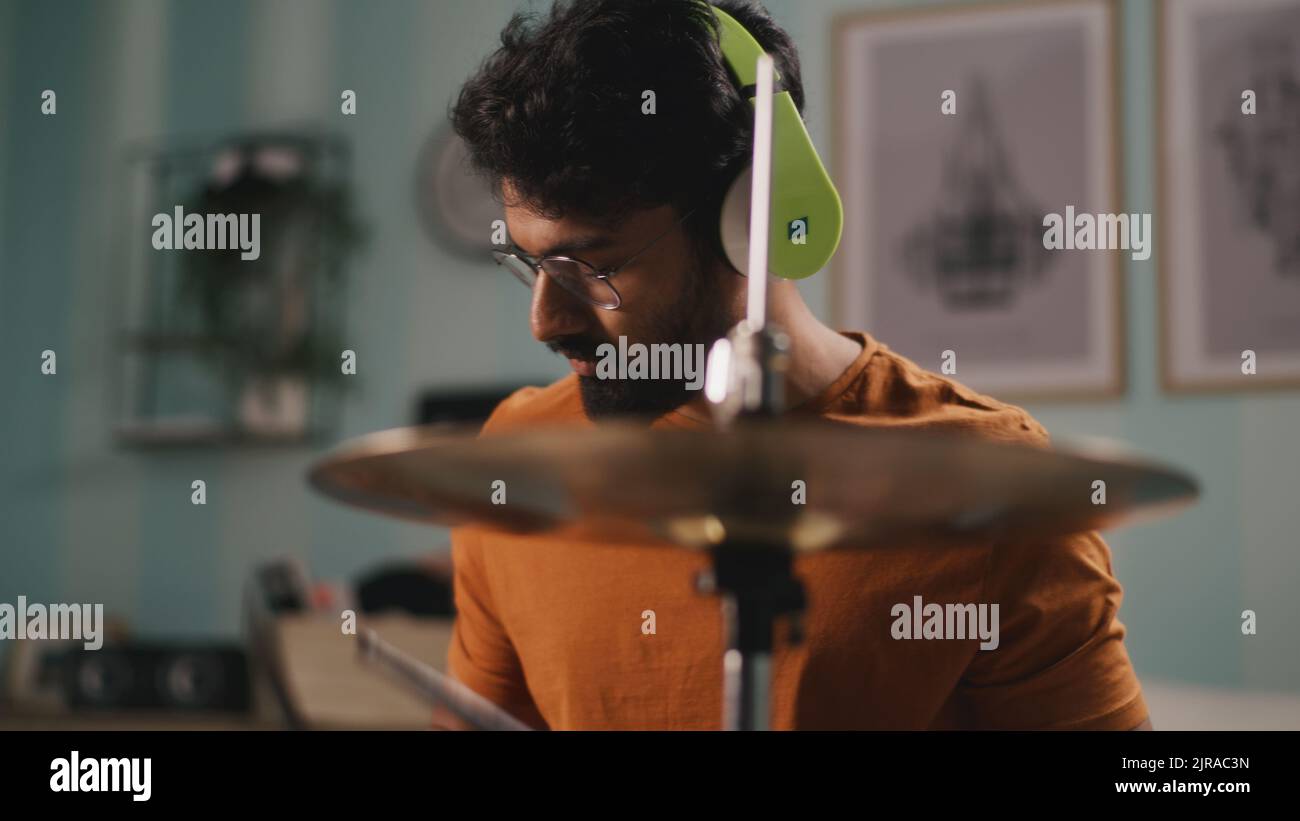 Bearded Indian drummer in wireless headphones playing rhythmic tune on ...