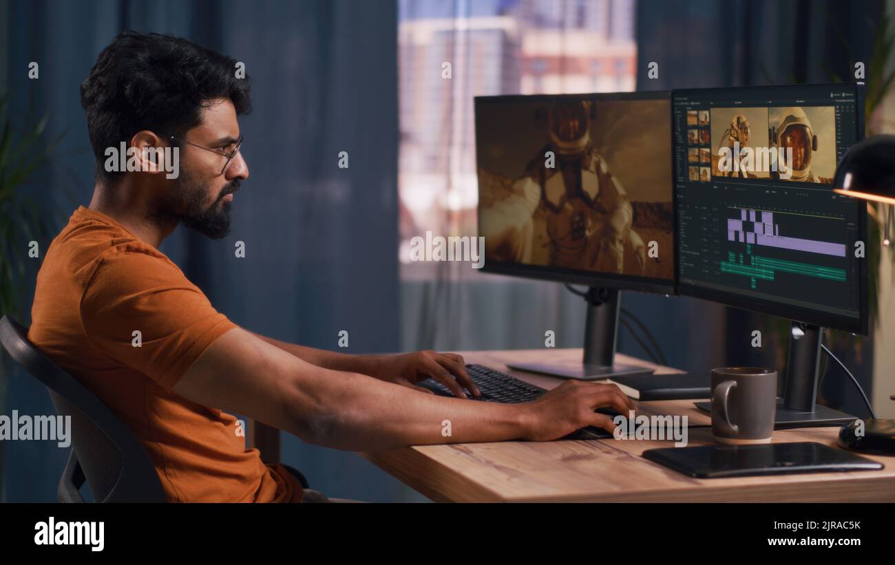 Back view of male content creator using computer to edit cosmonaut ...
