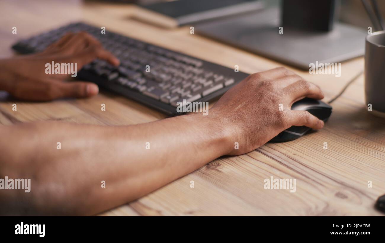 Unrecognizable man sitting at table in workplace and using computer mouse and keyboard Stock ...