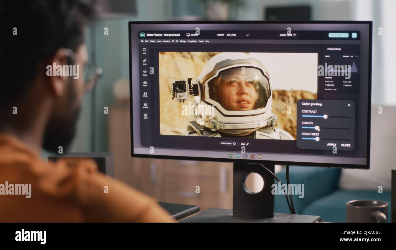 Back view of unrecognizable male retouching astronaut photo on computer ...