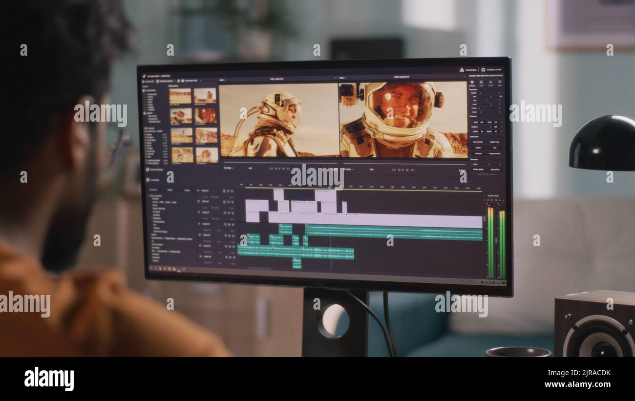 Back view of male content creator using computer to edit cosmonaut ...