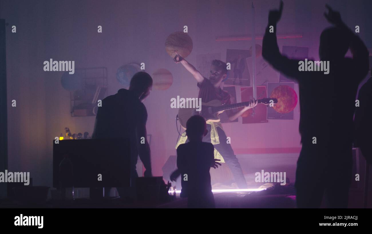 Father and siblings dancing and applauding to teenager playing electric ...