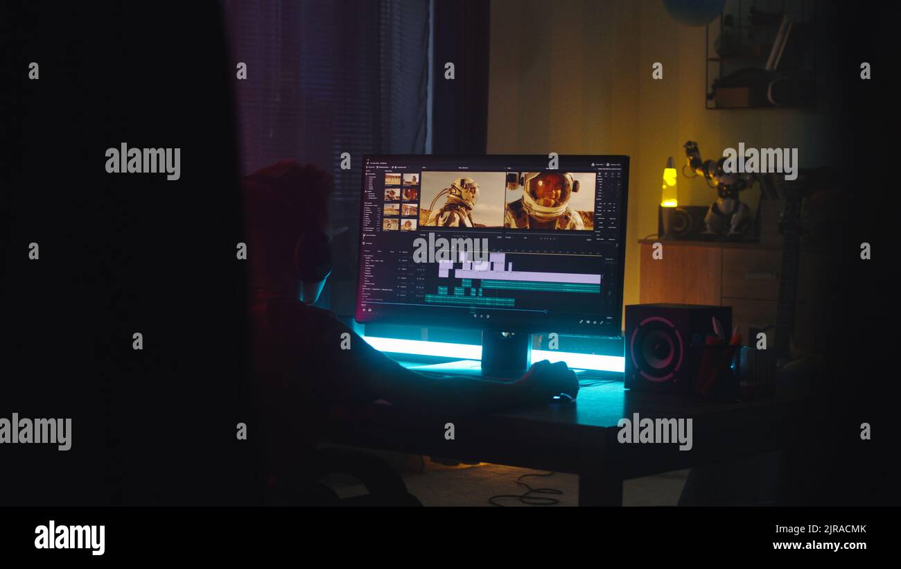 Teenager using computer to edit footage while sitting at desk in ...