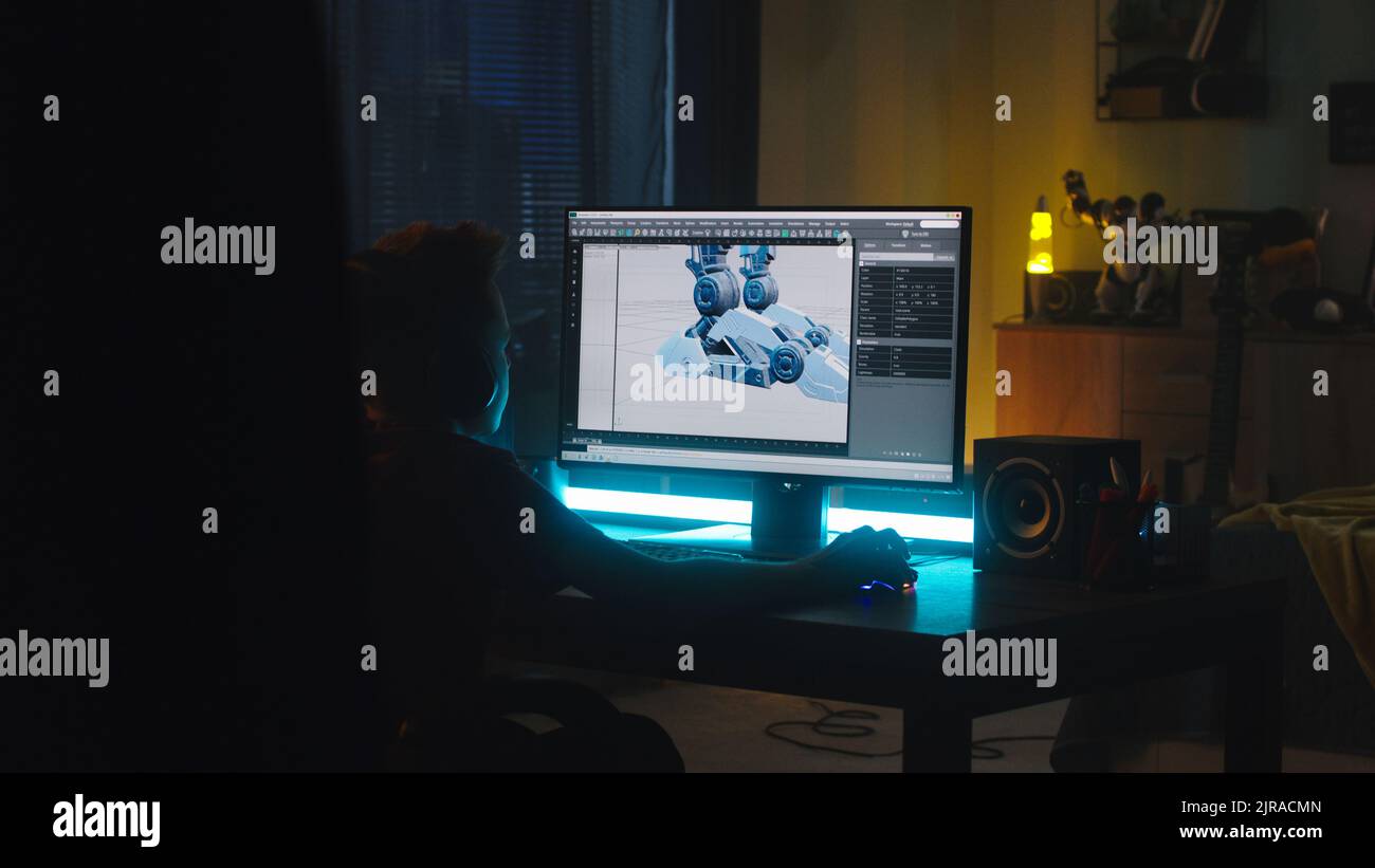 Anonymous teenager in headphones making 3D model of robot on computer ...