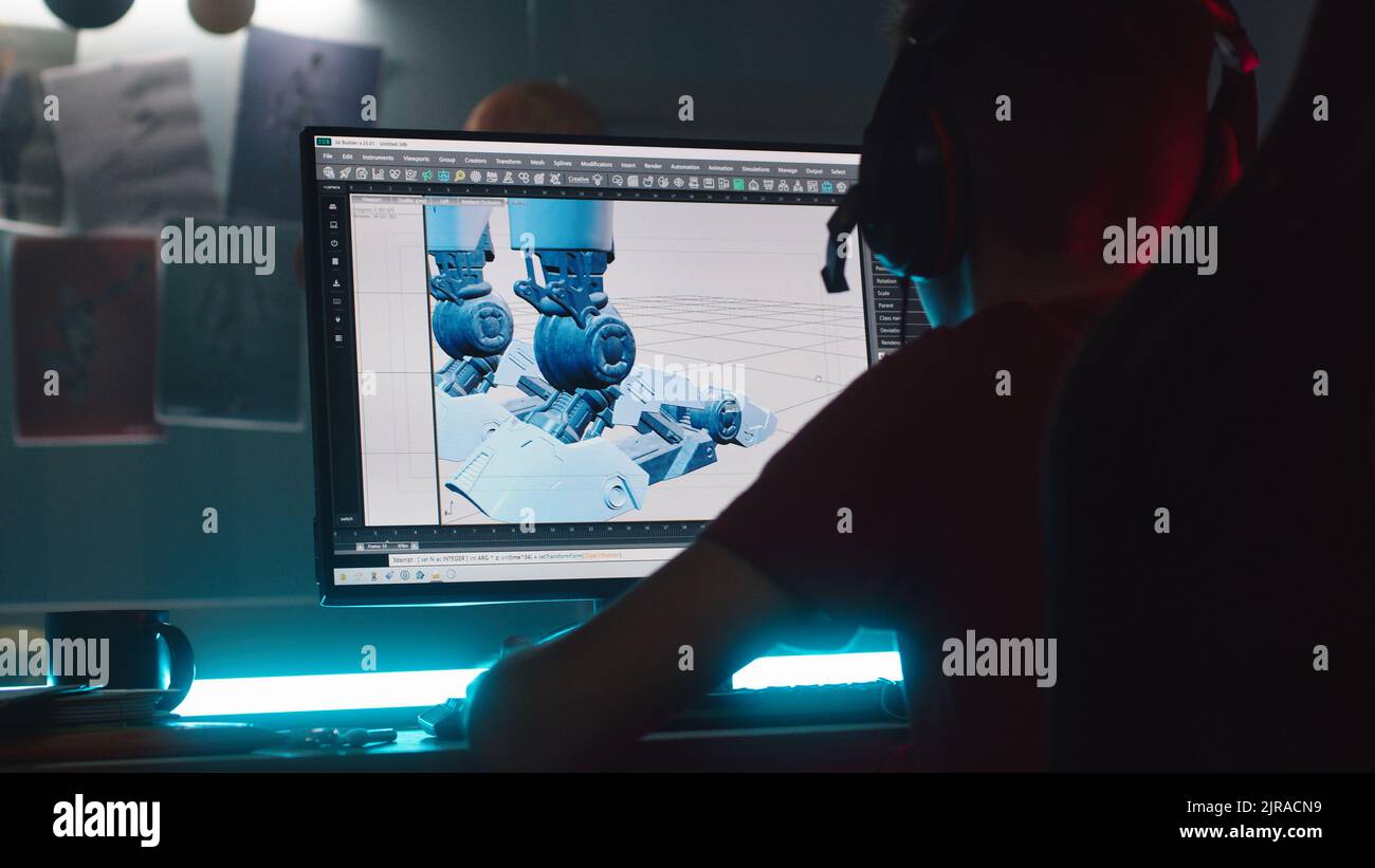 Anonymous teenager in headphones making 3D model of robot on computer ...