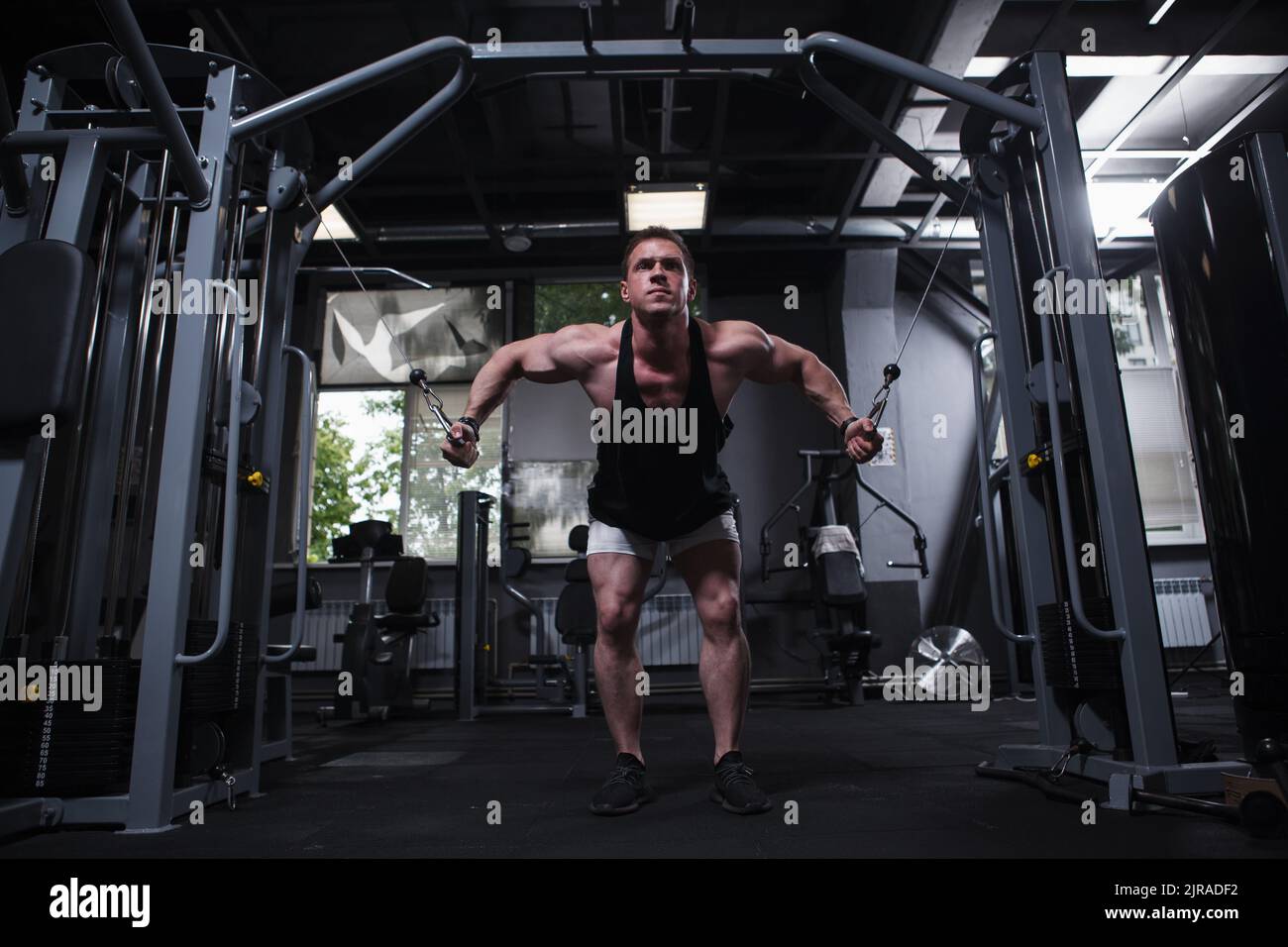 Full length shot of a bodybuilder exercising in cable crossover gym ...