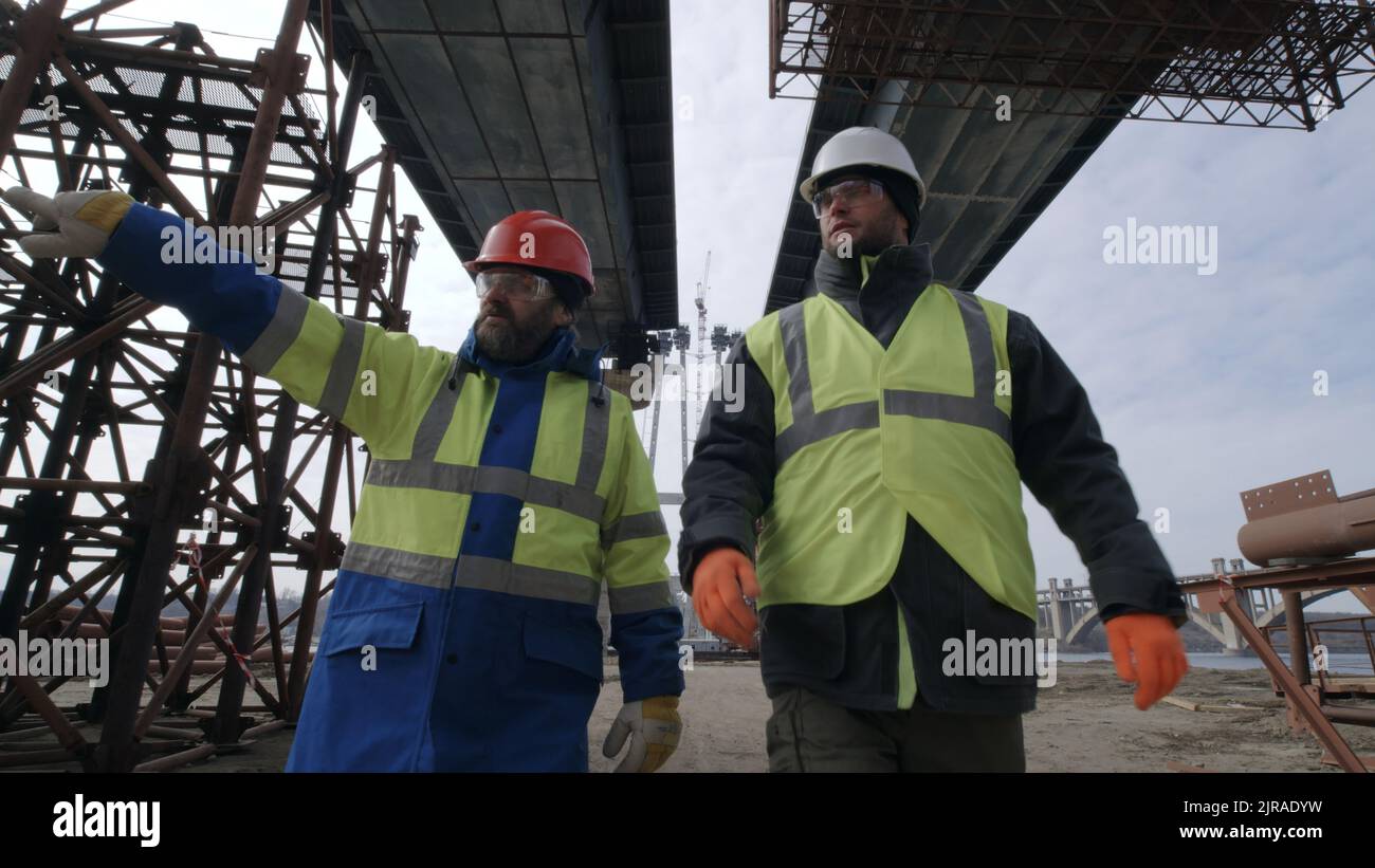 Men in uniform walking under bridge and talking during work on ...