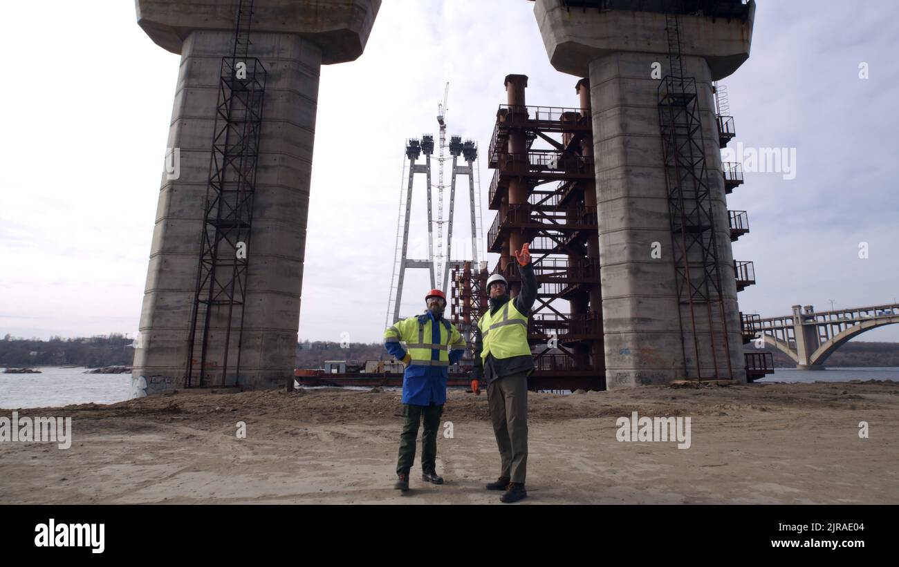 Men in uniform walking under bridge and talking during work on ...