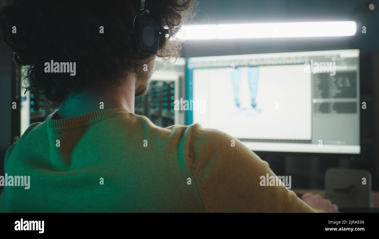 Rack focus of crop guy rendering 3D animation of walking robot while ...