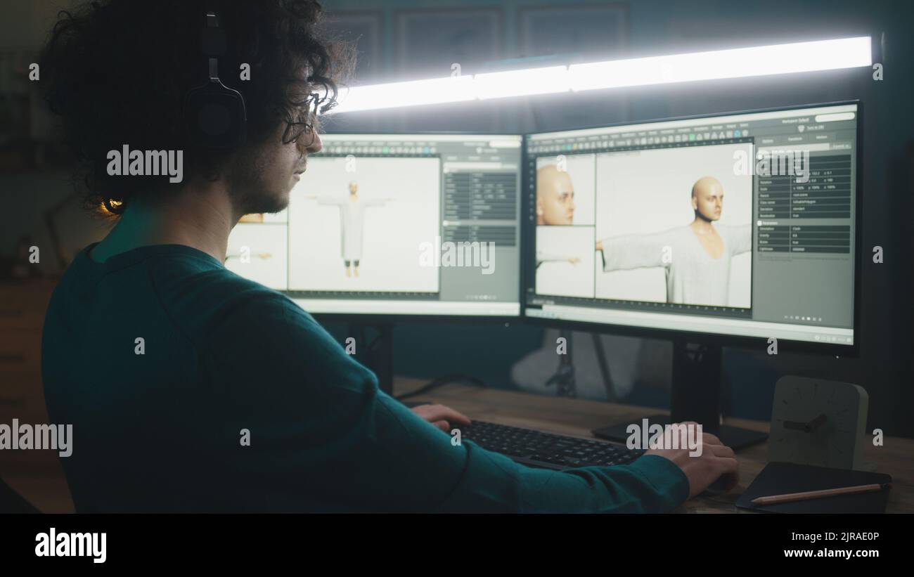 Male 3D designer creating character for videogame while working on remote project late at night ...