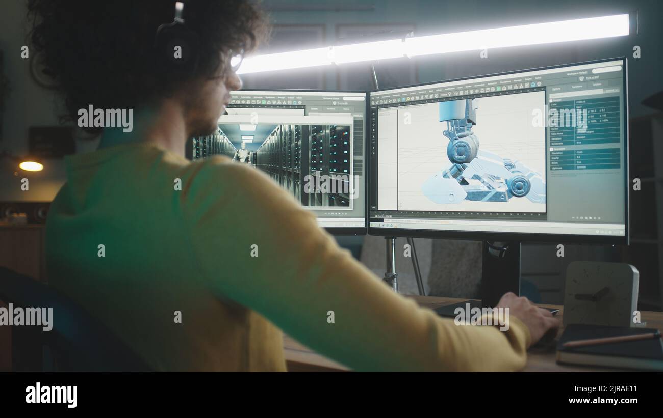 Man with curly hair creating 3D model of futuristic robot for videogame while working on remote ...