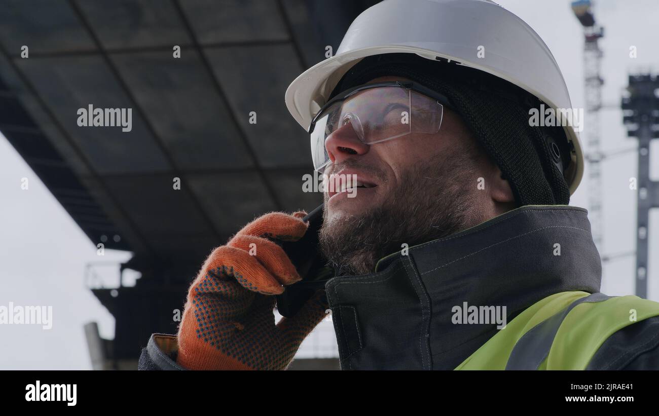From below man in hardhat and goggles looking up and speaking on ...