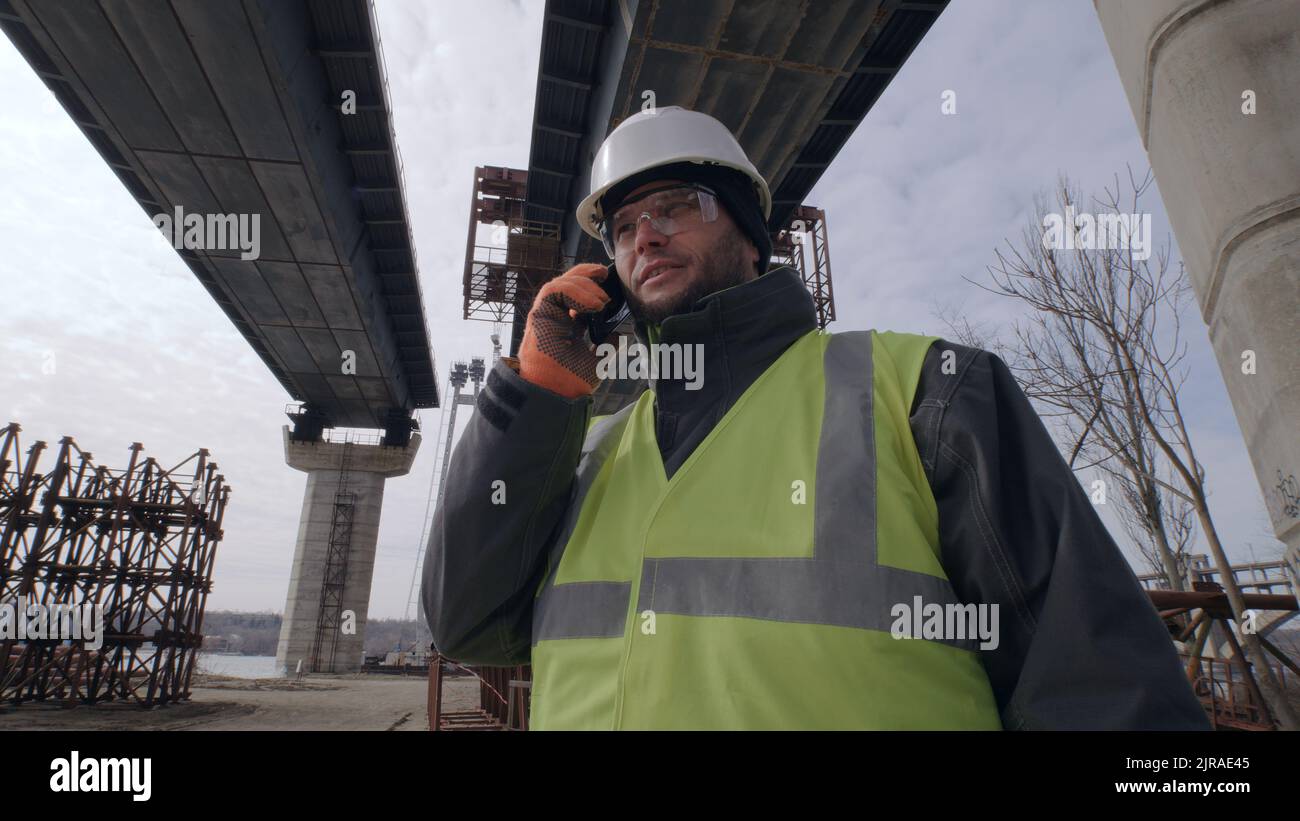 From below man in hardhat and goggles answering phone call while ...