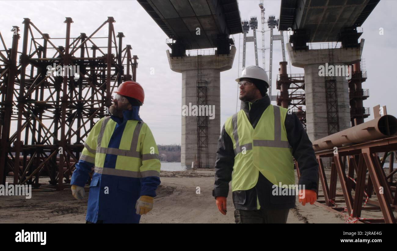 Men in uniform walking under bridge and talking during work on ...