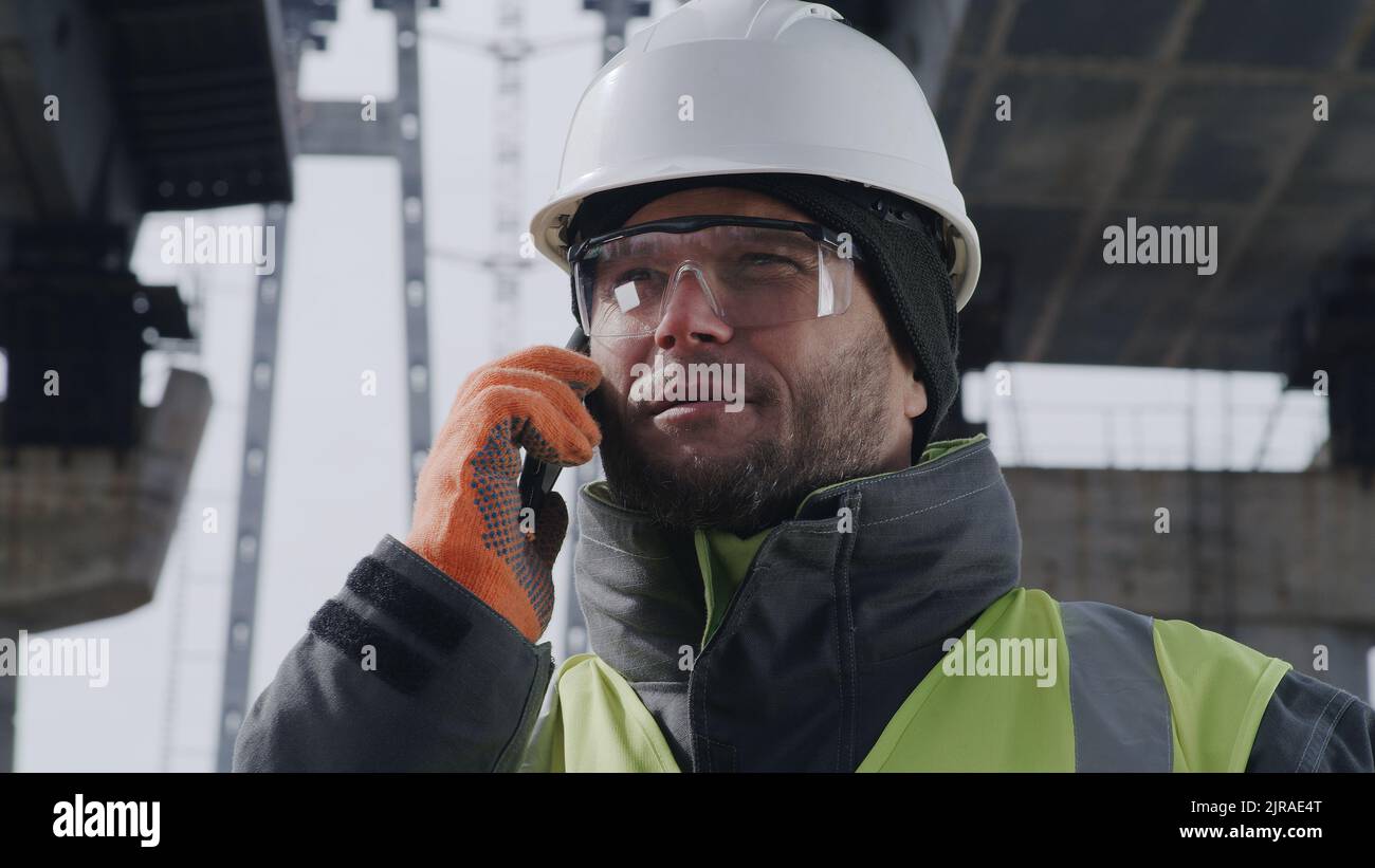 From below man in hardhat and goggles looking up and speaking on ...