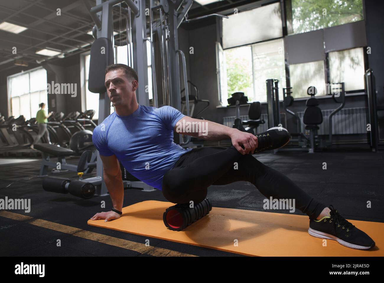 Professional bodybuilder using foam roller, stretching body muscles ...