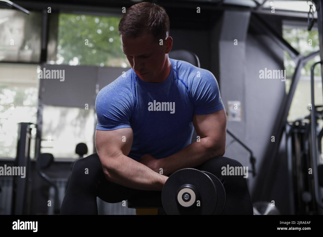 Strong muscular bodybuilder doing bicep curls with heavy dumbbell at ...