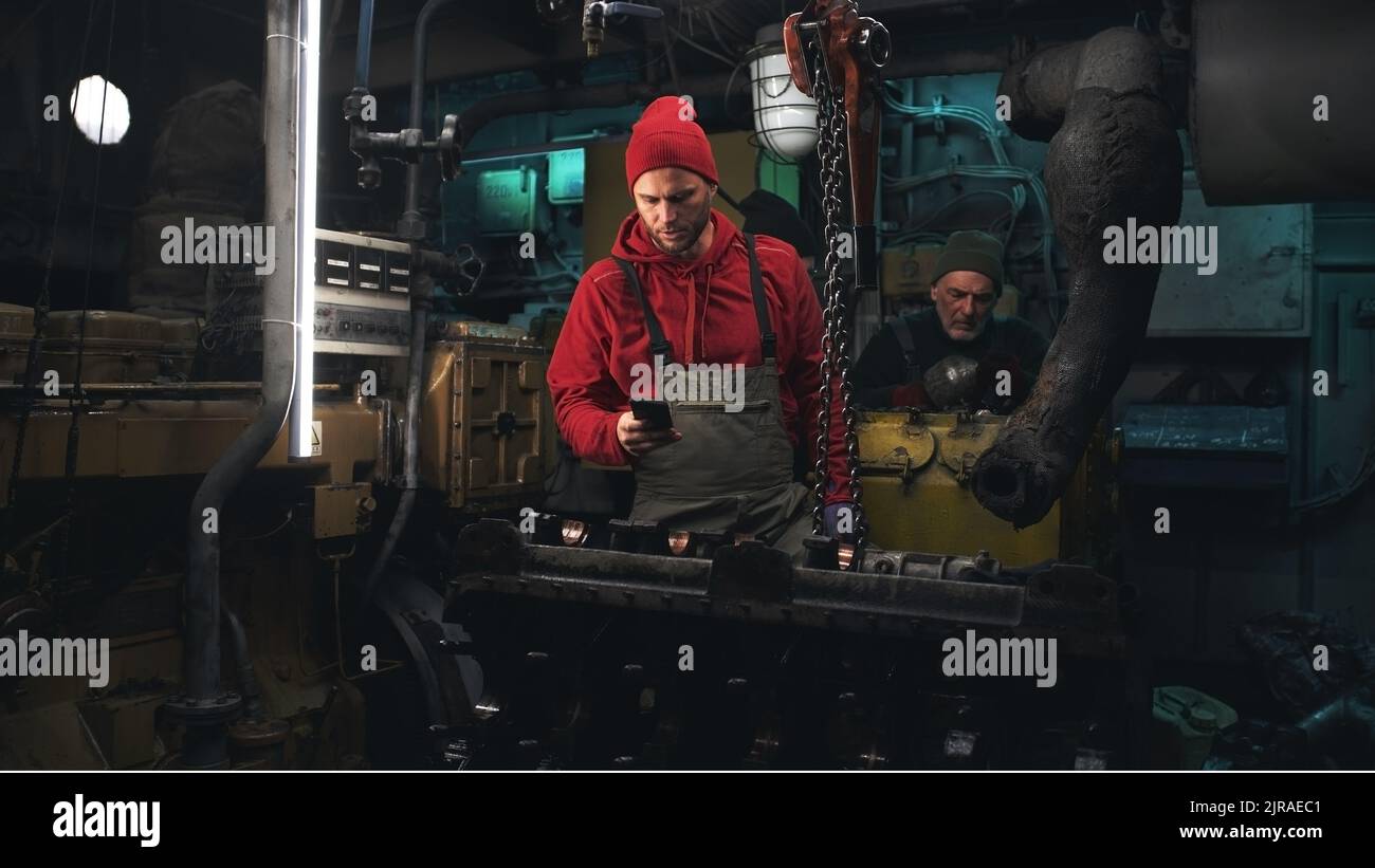 Zoom in view of male engineer making phone call while repairing motor ...