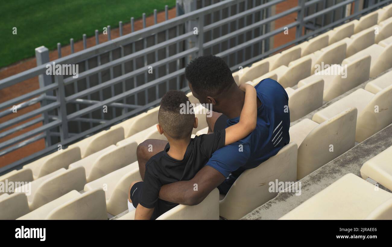 From above African American man embracing mixed race boy and speaking ...