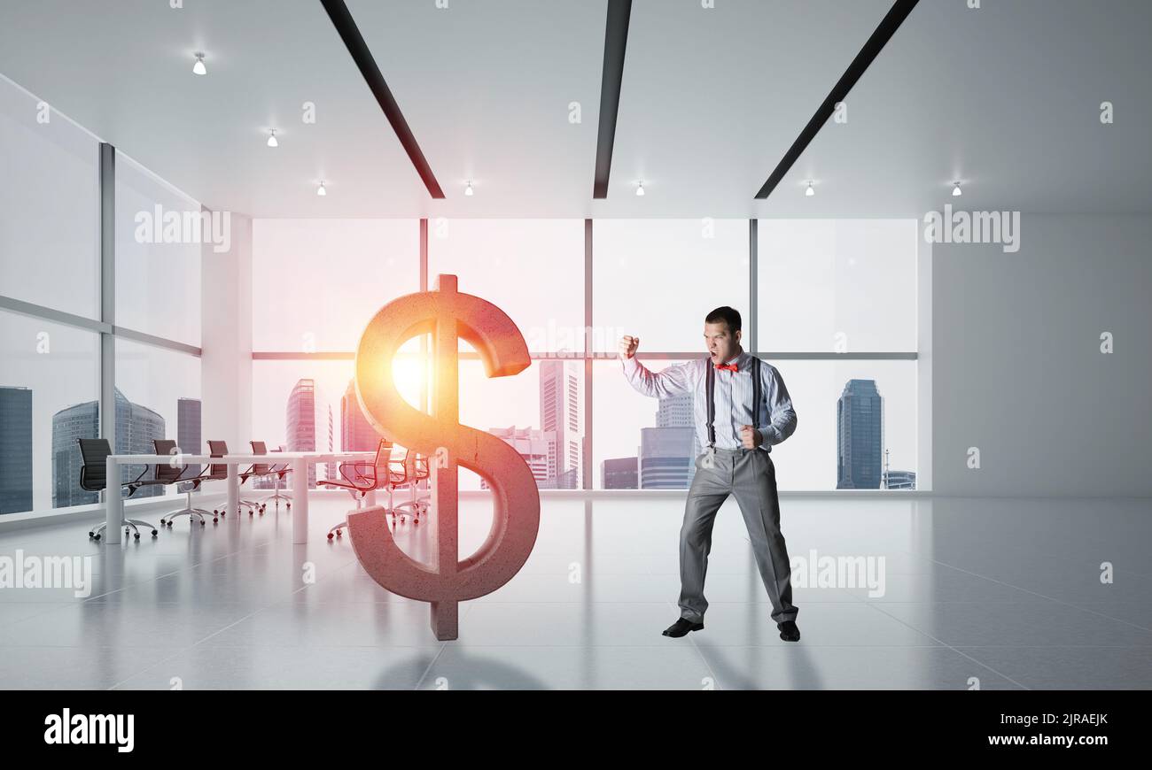 Determined banker man in modern office interior breaking dollar figure ...