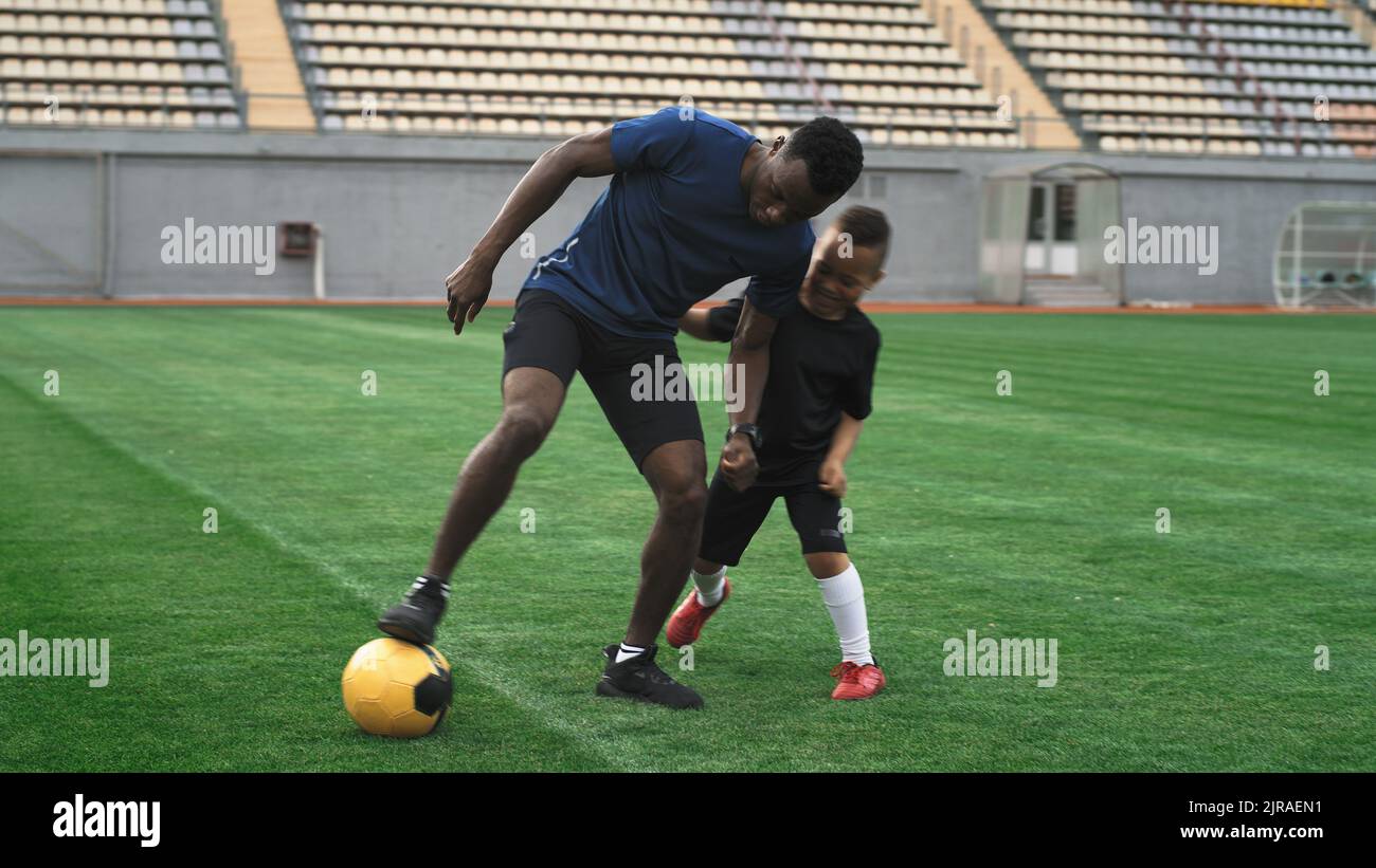 Tracking shot of black man trying to take ball from mixed race boy ...