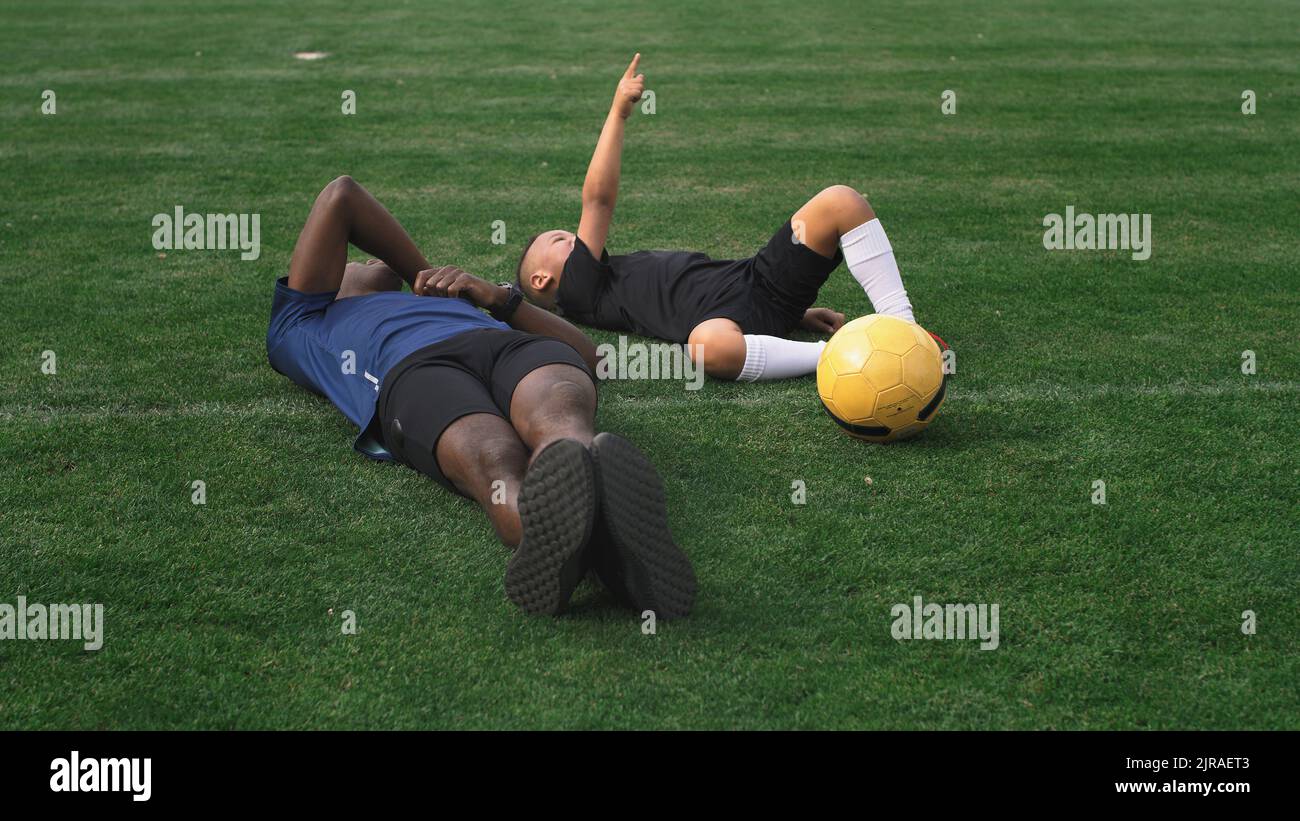 Zoom out view of black man pointing at sky and speaking with mixed race ...