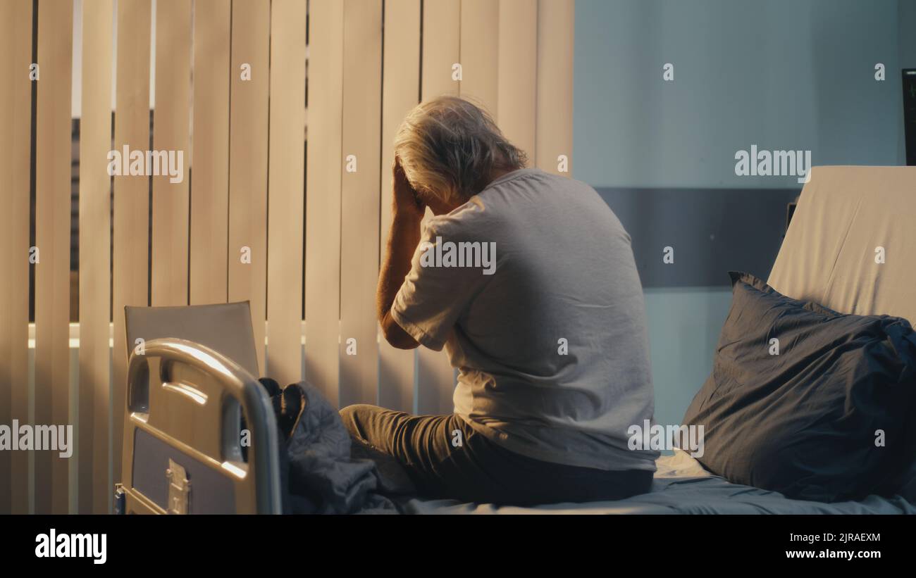 Back view of unhappy senior man touching face and crying while sitting ...