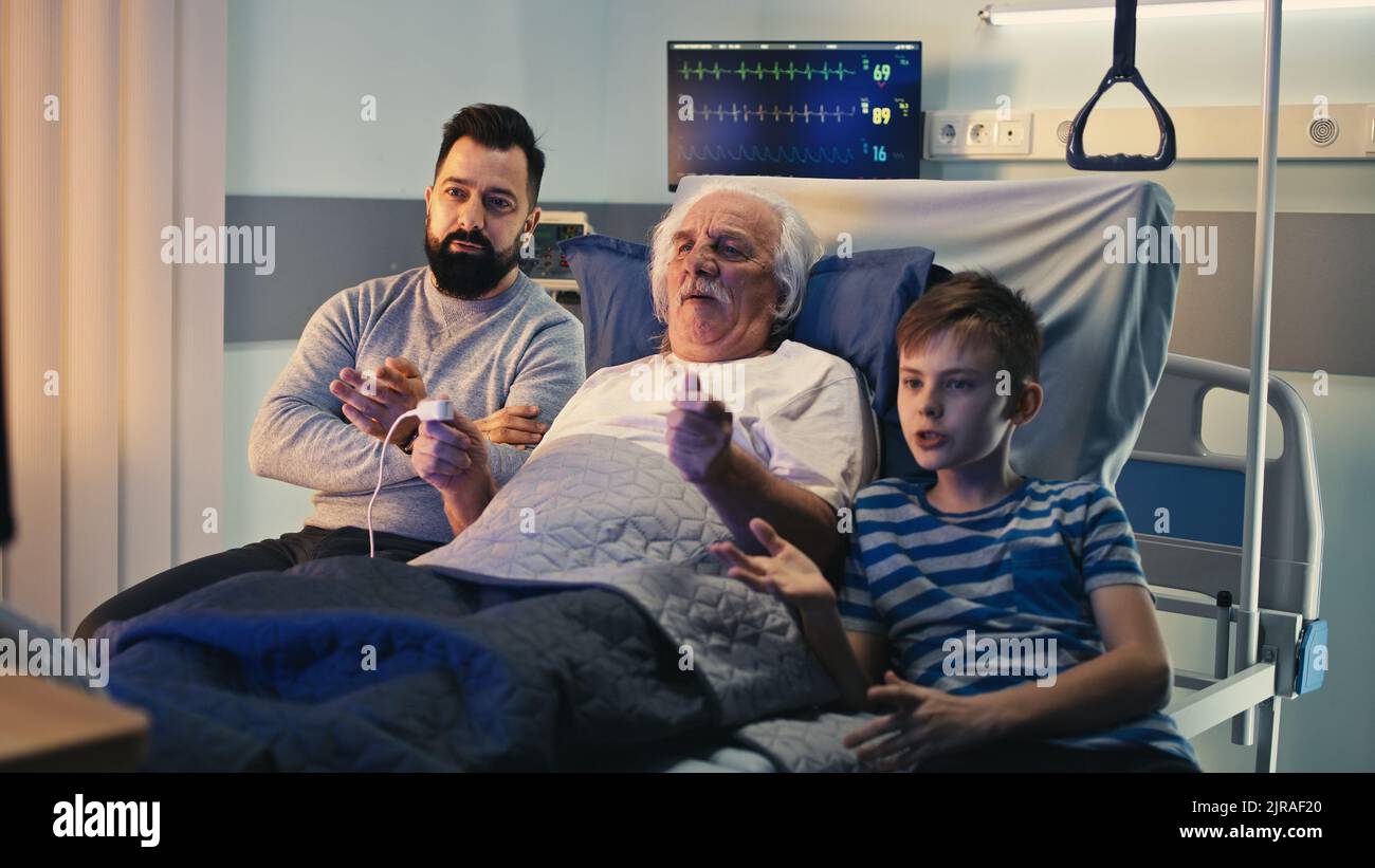 Senior male patient discussing match with adult man and boy then ...