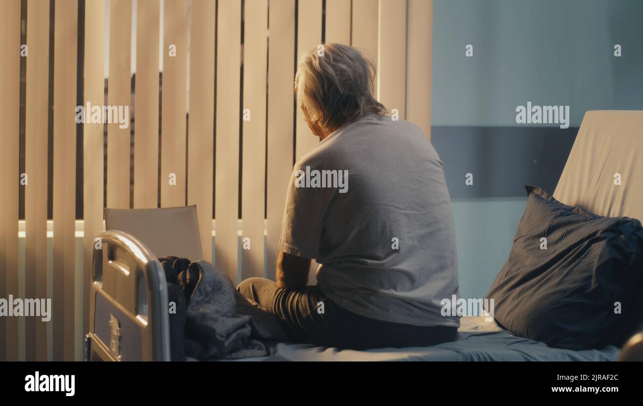 Back view of unhappy senior man touching face and crying while sitting ...