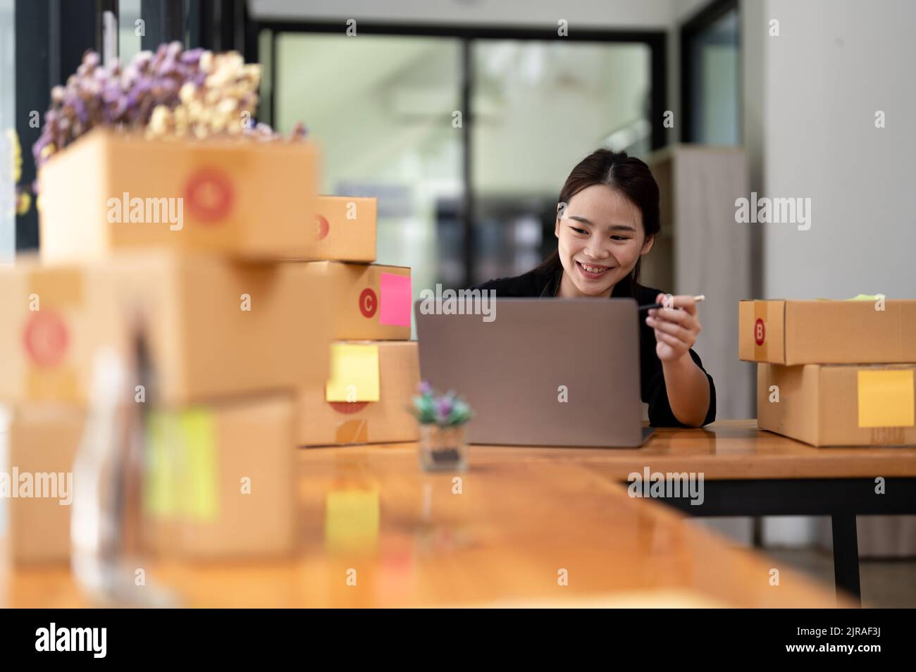 Business woman owner with parcel box for delivery and using laptop at ...