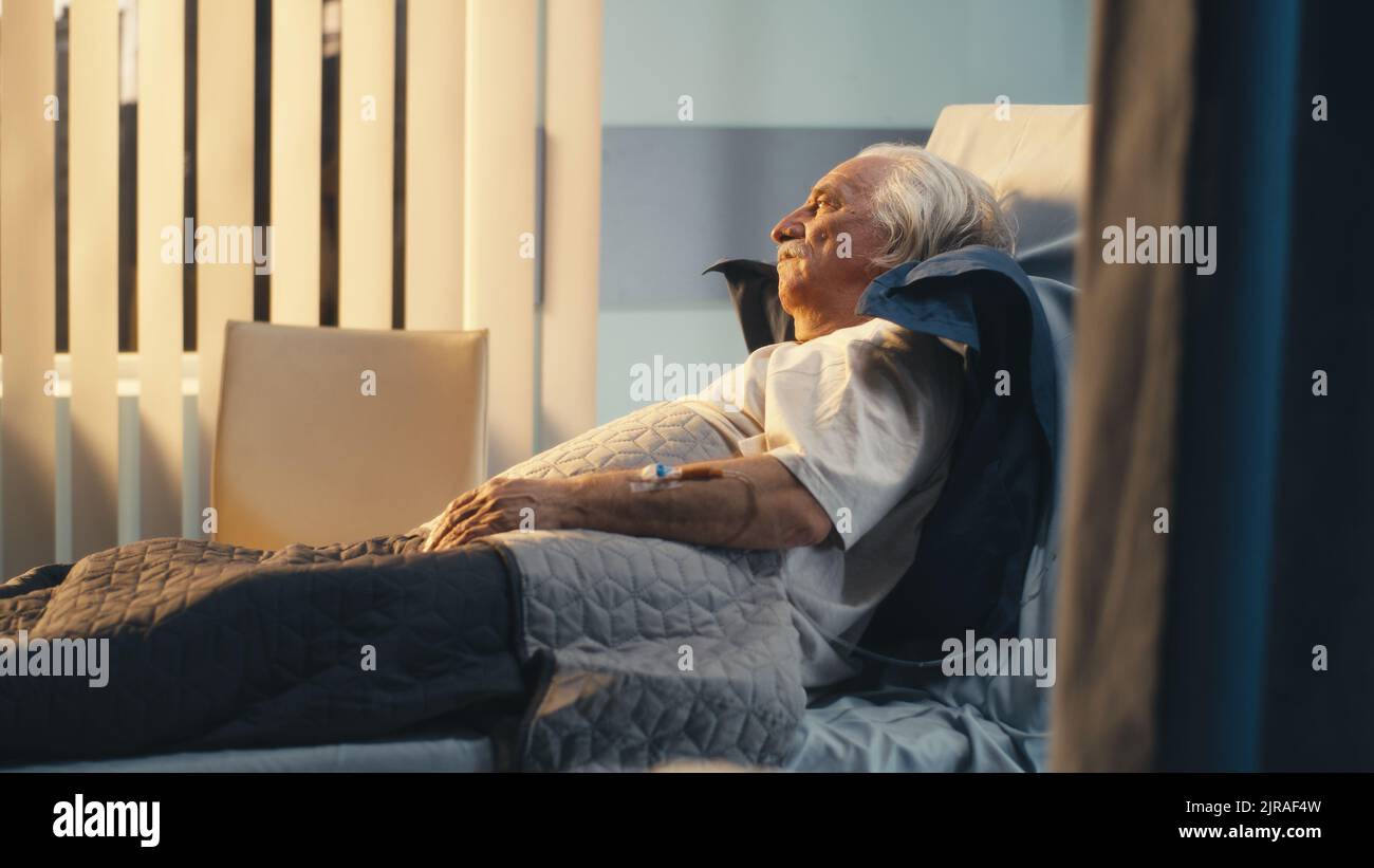 Pan left view of lonely elderly man lying on bed and looking away in ...