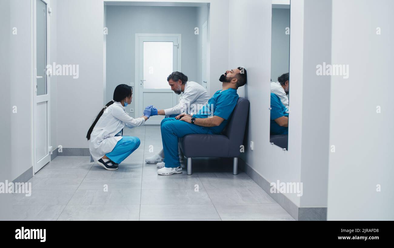 Female medical practitioner walking in hallway and joining men then ...
