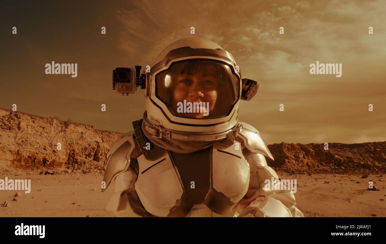 Positive woman in spacesuit smiling and looking at camera while ...