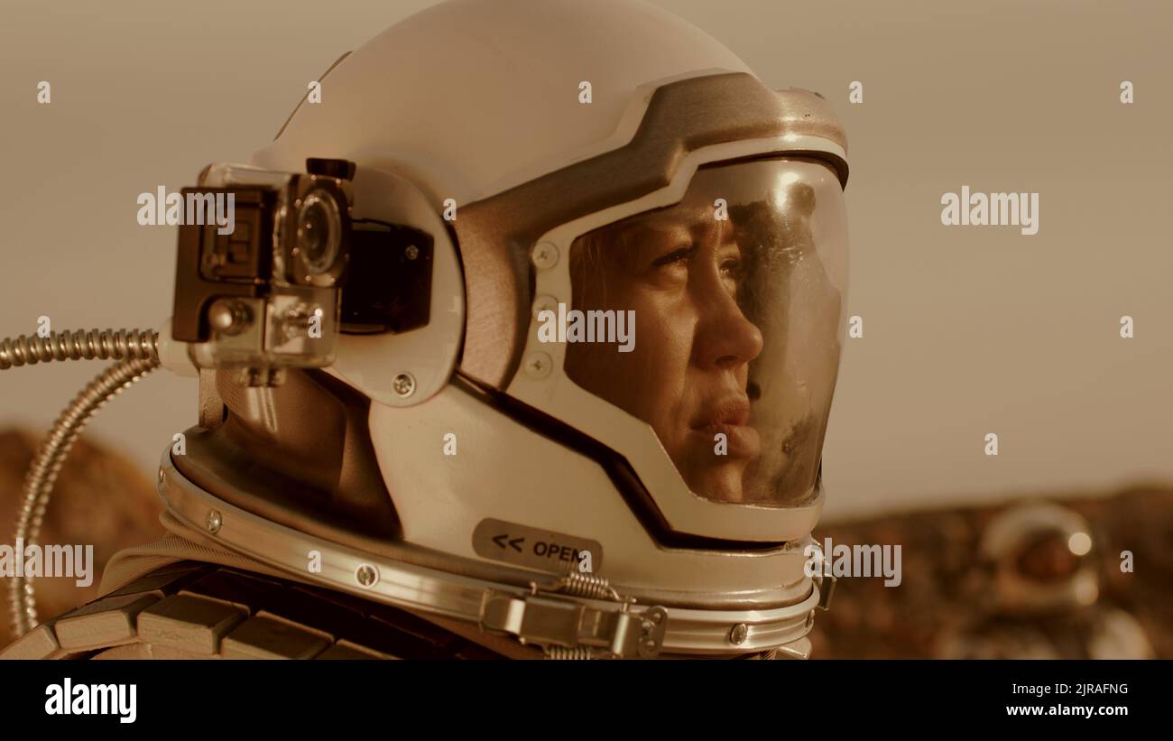 Woman with camera on spacesuit helmet looking around and talking while ...
