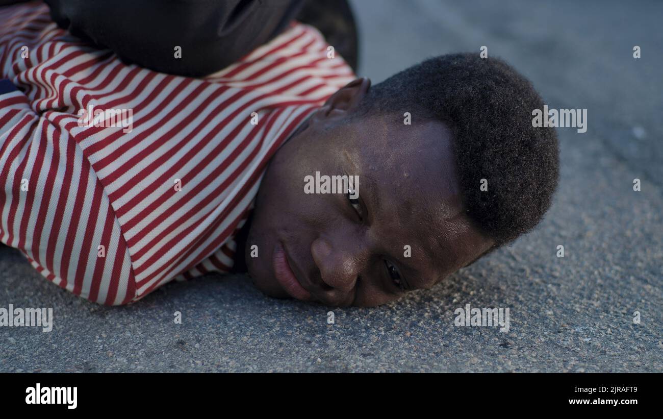 Crop police officer pressing resisting black man to ground and putting ...