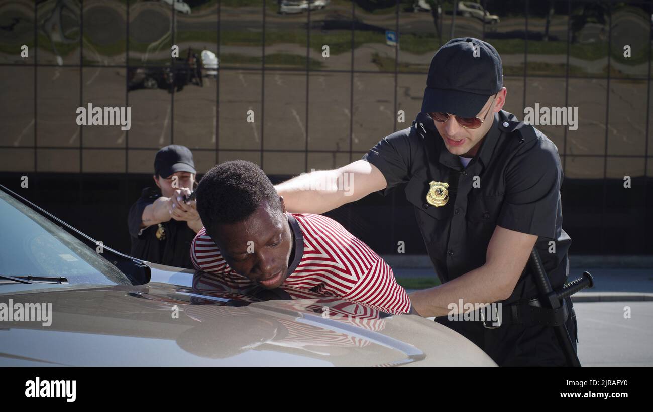 Man and woman in police uniform aiming pistol and searching resisting ...