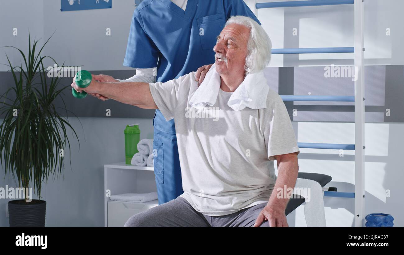 Male and female rehabilitation therapists showing and helping senior ...