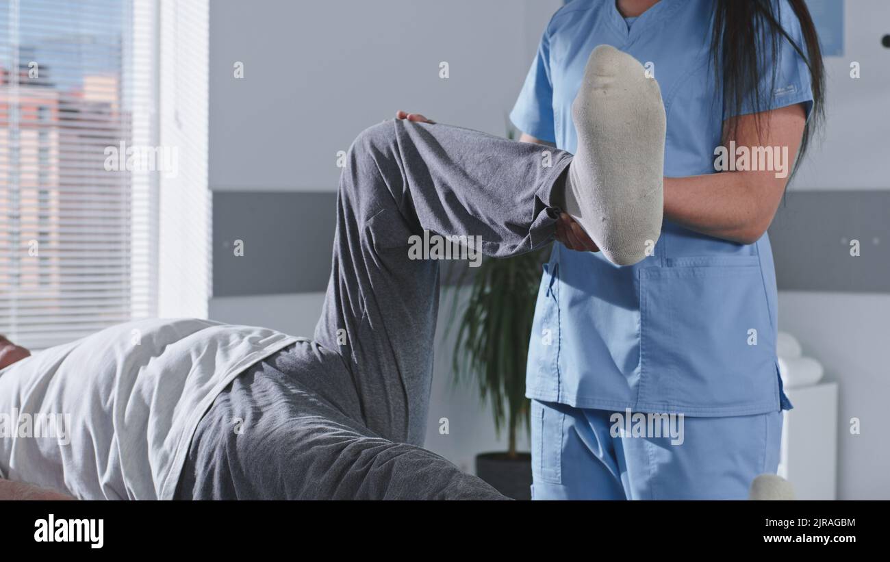 Female therapist talking with senior man while bending and stretching ...