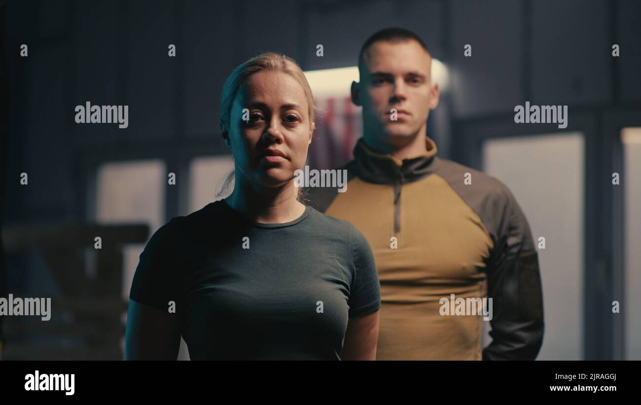 Male and female athletes looking at camera with serious faces in dark ...