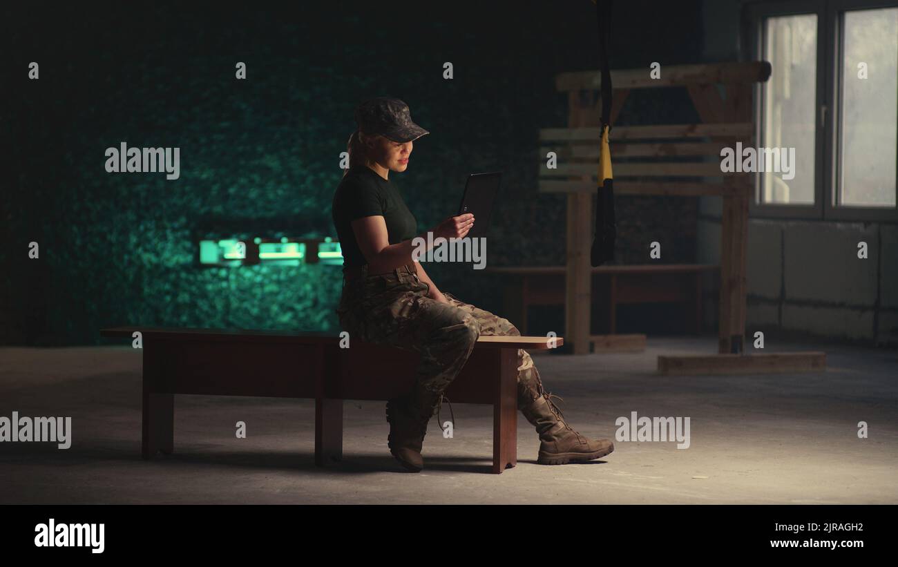 View of delighted female soldier smiling and waving hand while sitting ...