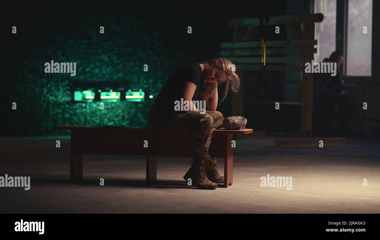 View of tired military woman taking off cap and touching hair while ...