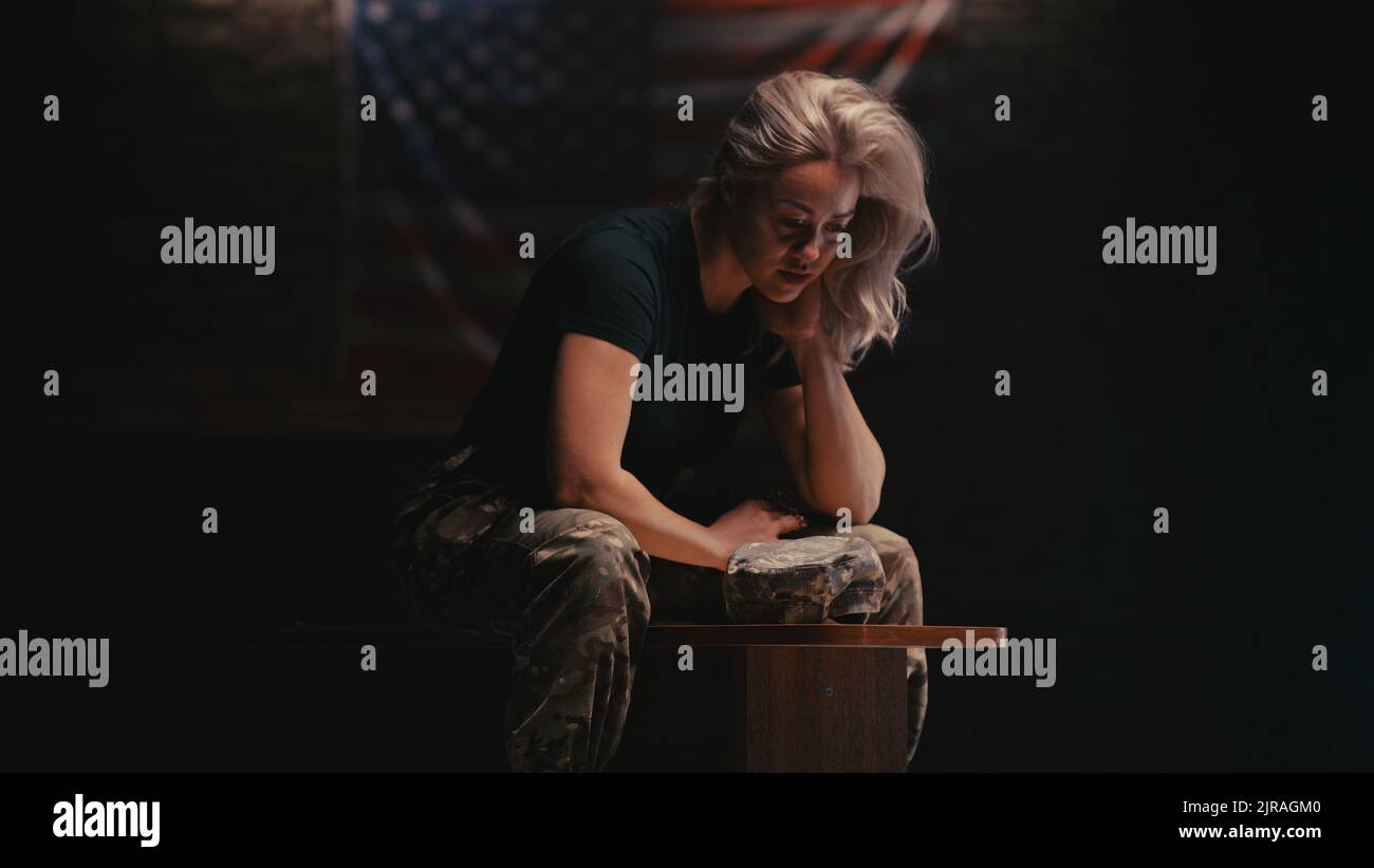 View of tired military woman taking off cap and touching hair while ...