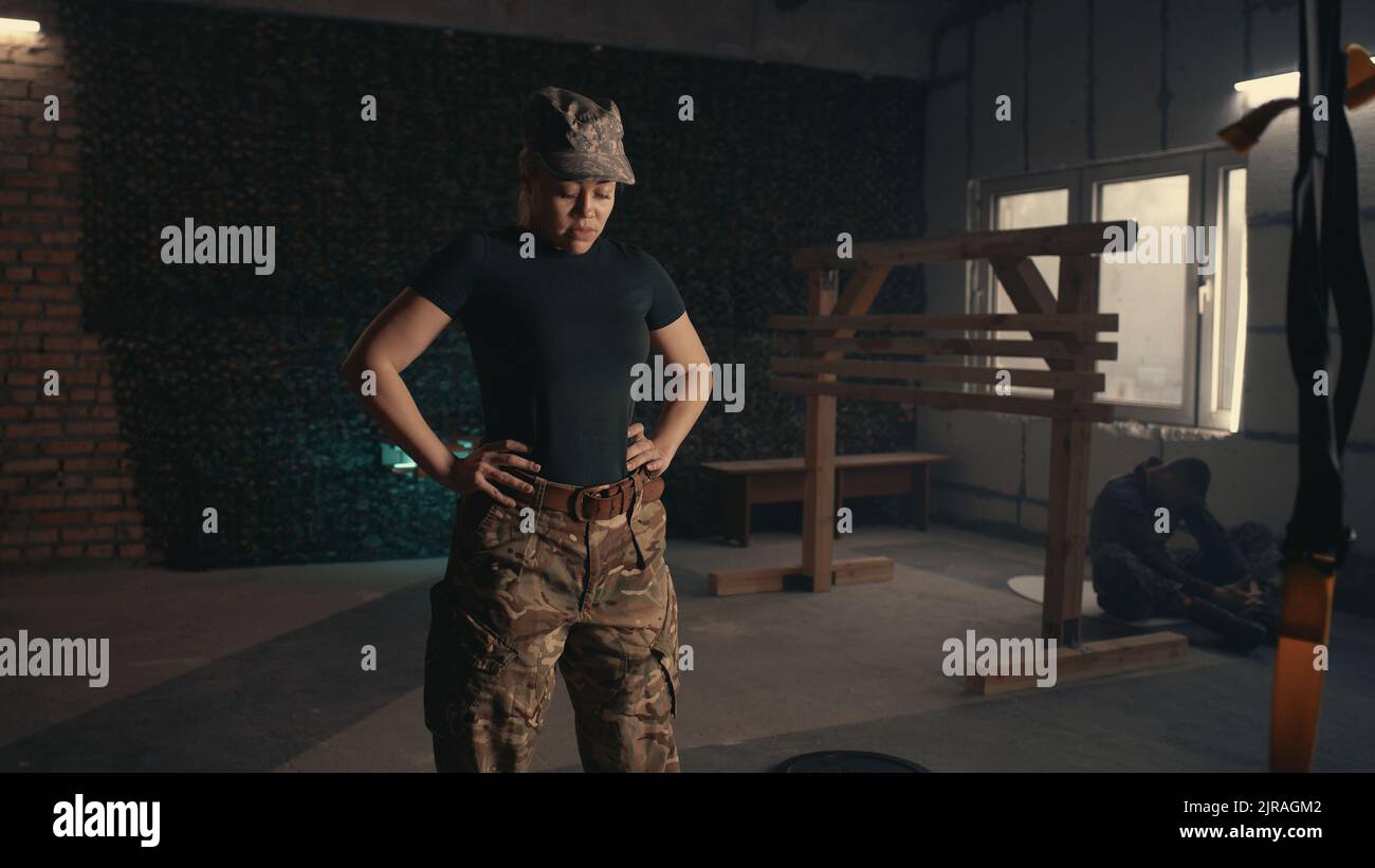 View of female soldier in camouflage stretching arms and shoulders ...