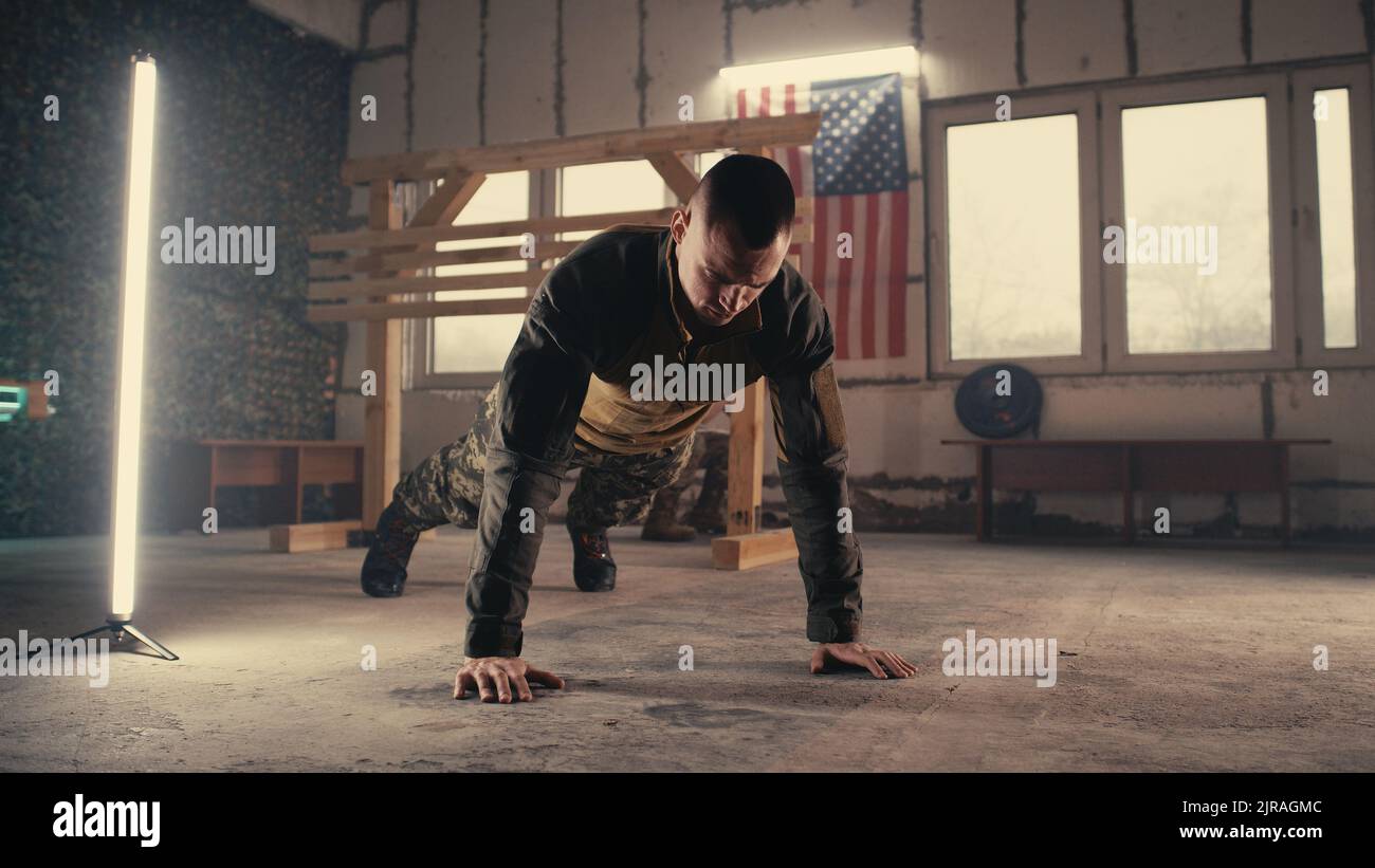 Strong man in camouflage sportswear doing push ups then taking break to ...